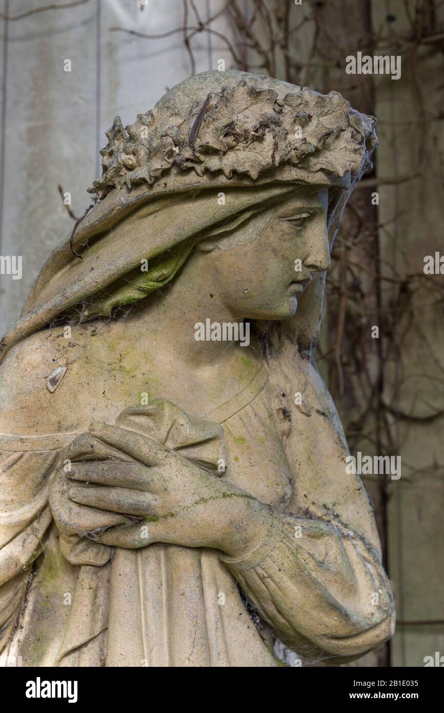 Old weathered female statue in the Orangery, Castle Ashby Gardens ...