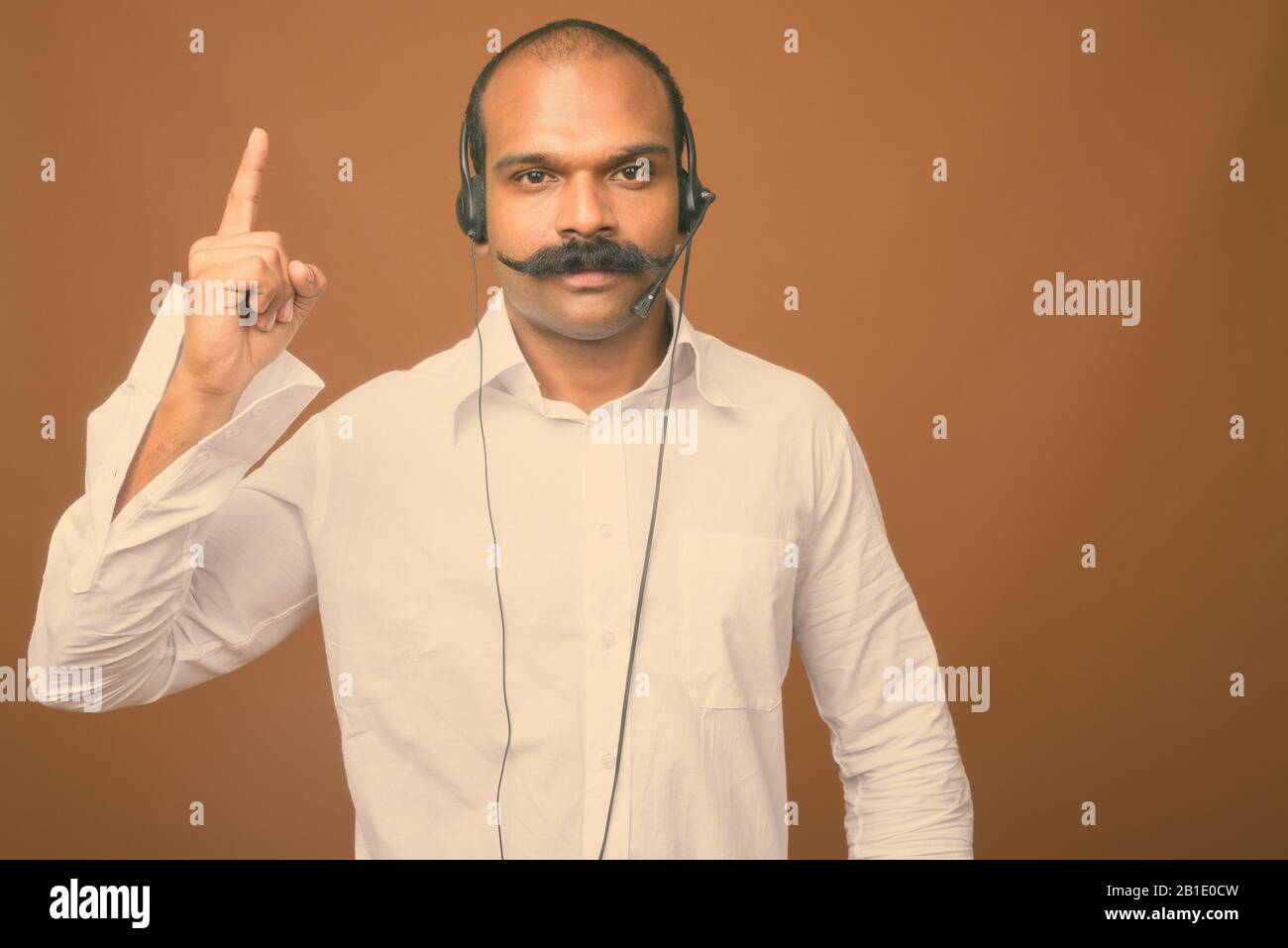Indian businessman wearing headset against brown background Stock Photo ...
