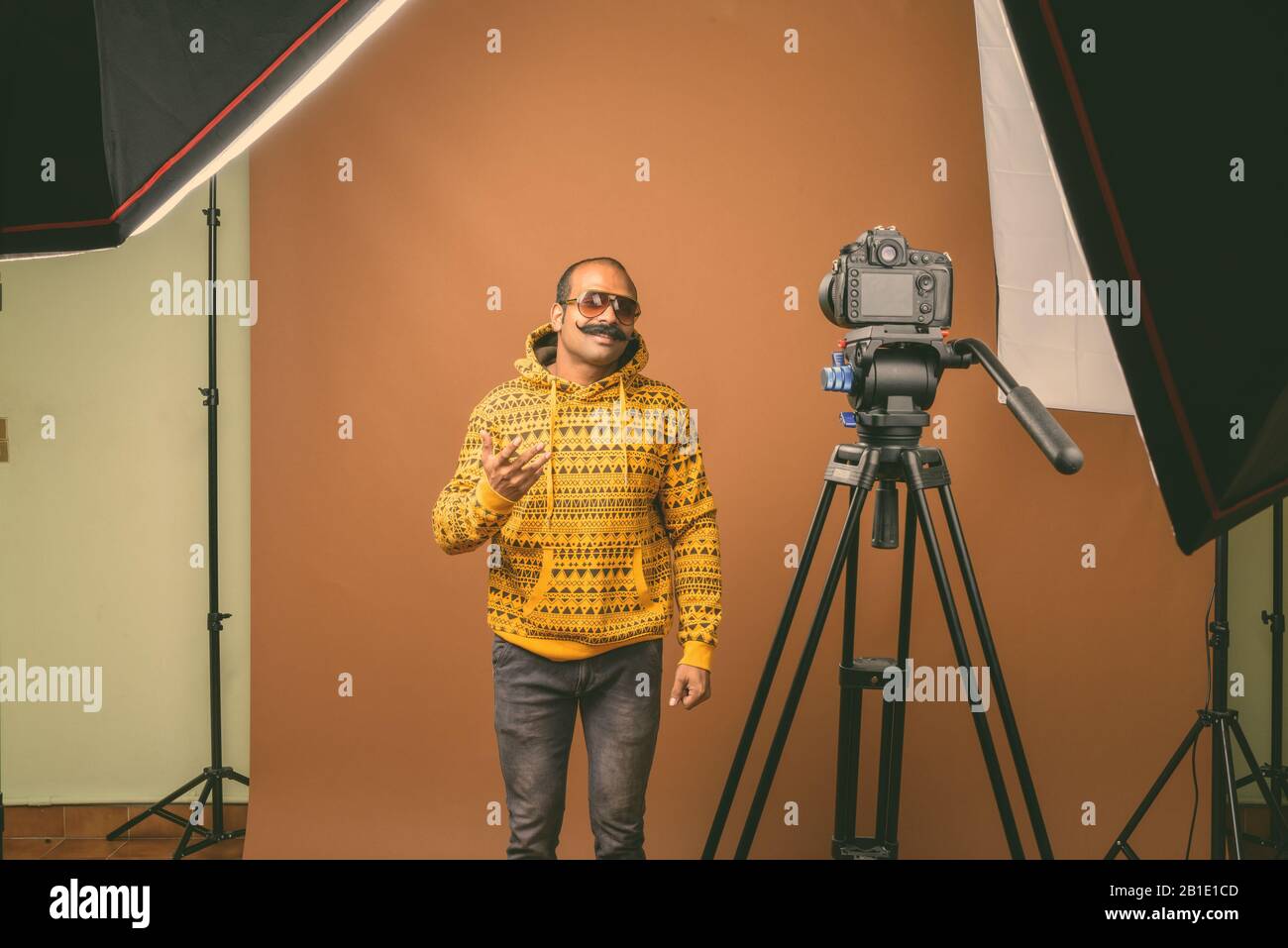 Indian man with mustache vlogging against brown background Stock Photo ...