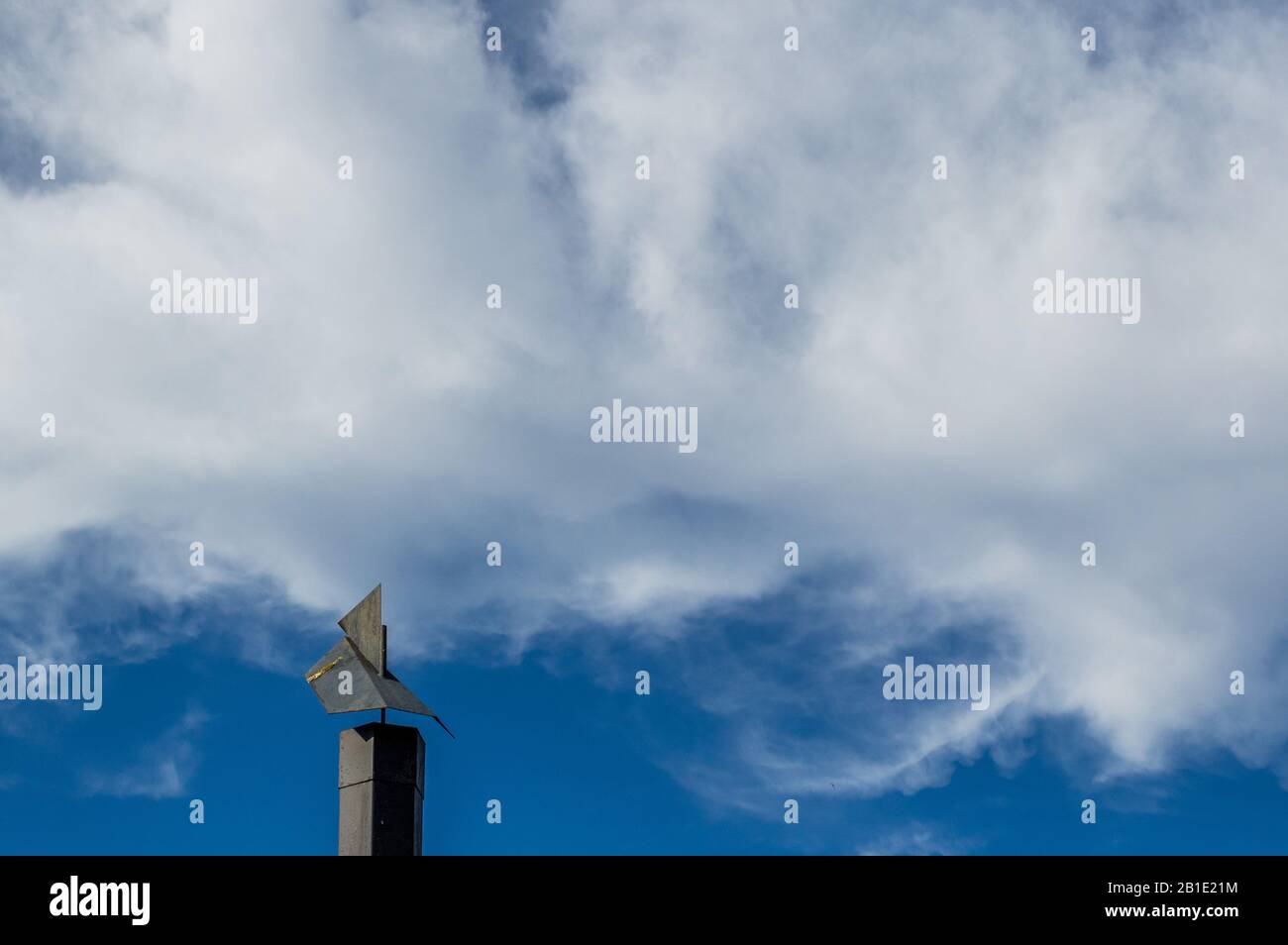 Top of a black metal chimney with a weather vane isolated against a ...