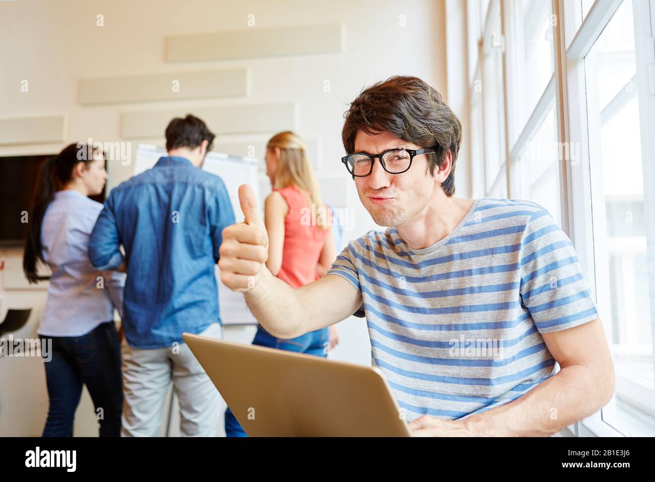 Nerd student on laptop computer holds his thumb up as a sign of ...