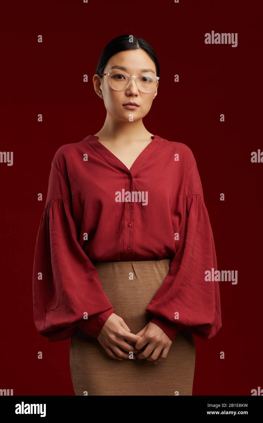 Professional portrait of elegant Asian woman standing by maroon ...