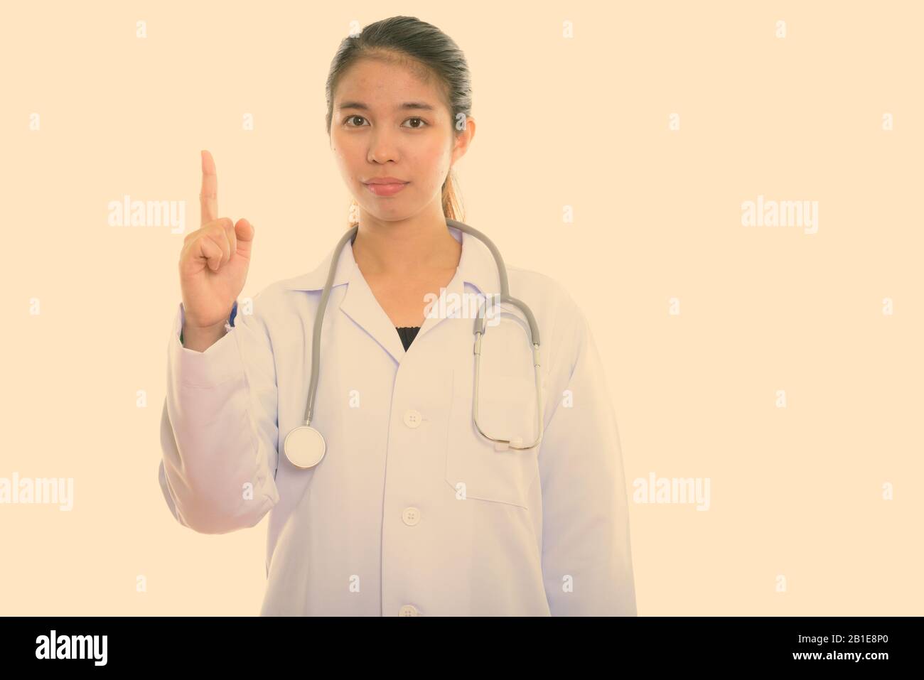 Studio shot of young Asian woman doctor pointing finger up Stock Photo ...