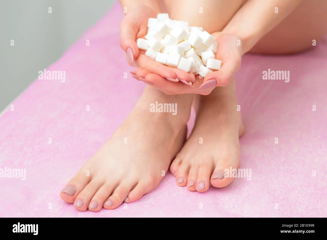 Female holding sugar cubes in her palms next to her smooth legs, close ...