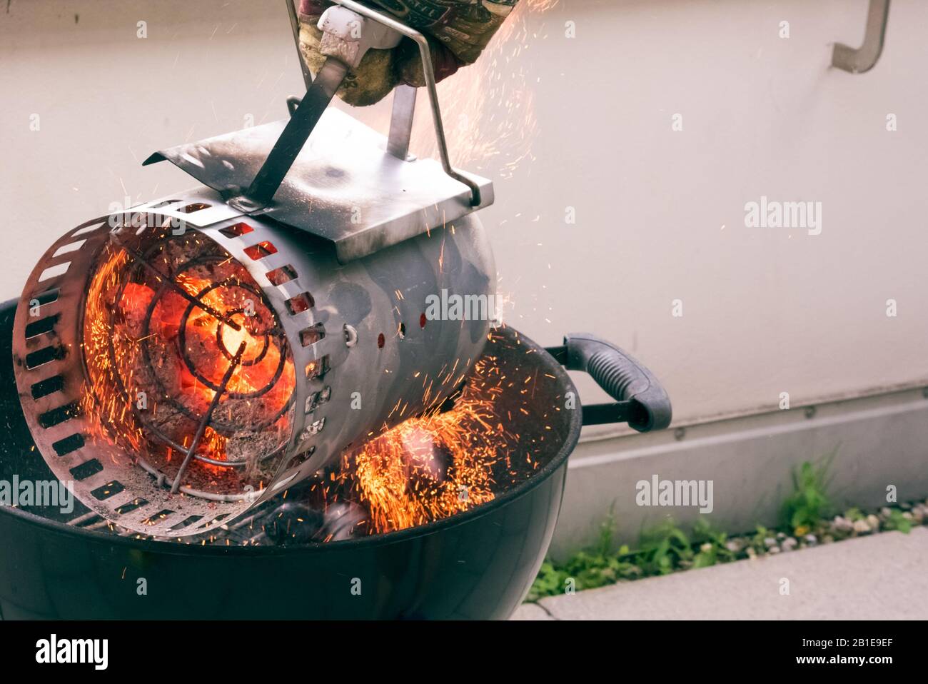 Pouring coal into a barbecue, with lots of fire and sparks everywhere ...