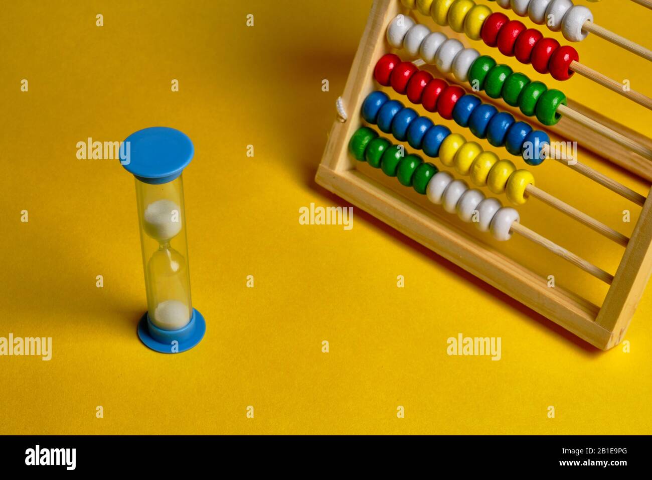 Blue hourglass and abacus at yellow background. Time management concept ...