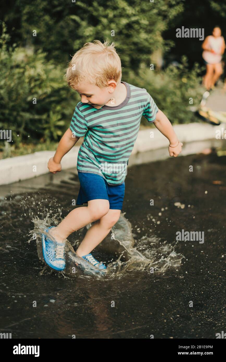 Boy jumping in a water puddle hi-res stock photography and images - Alamy