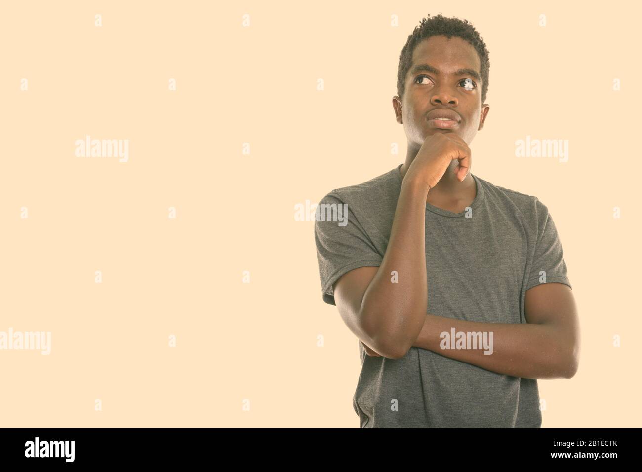 Studio shot of young black African teenage boy thinking while looking ...