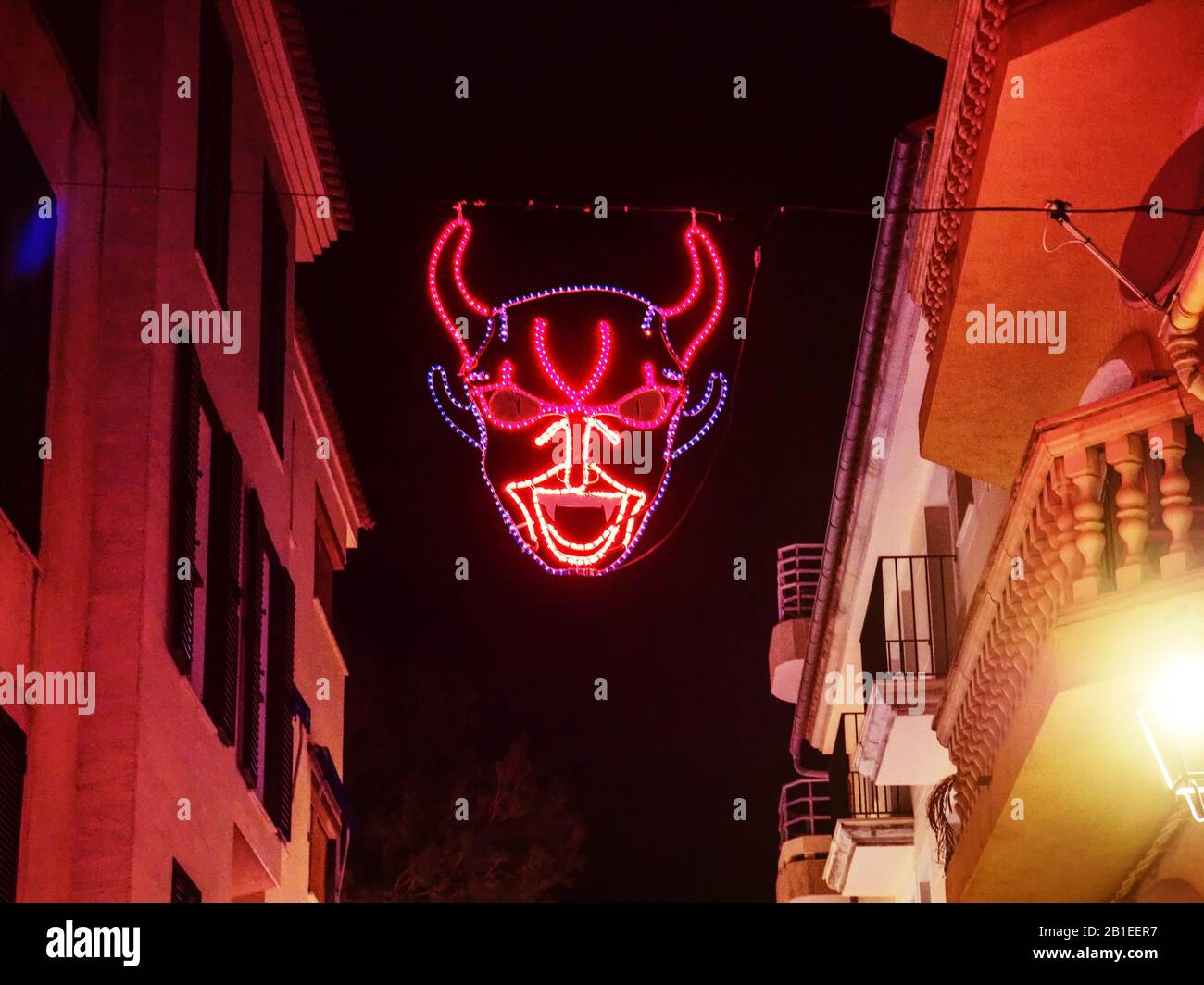 Shinning red mask of devil on black night background. Night street with ...