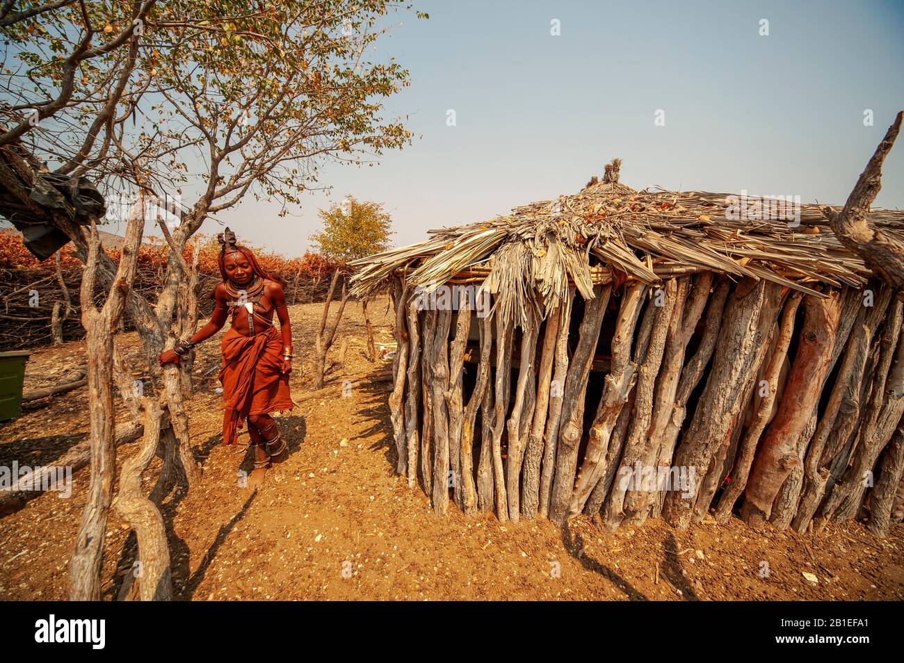 Himba woman with traditional clothes near his primitive hut at his ...