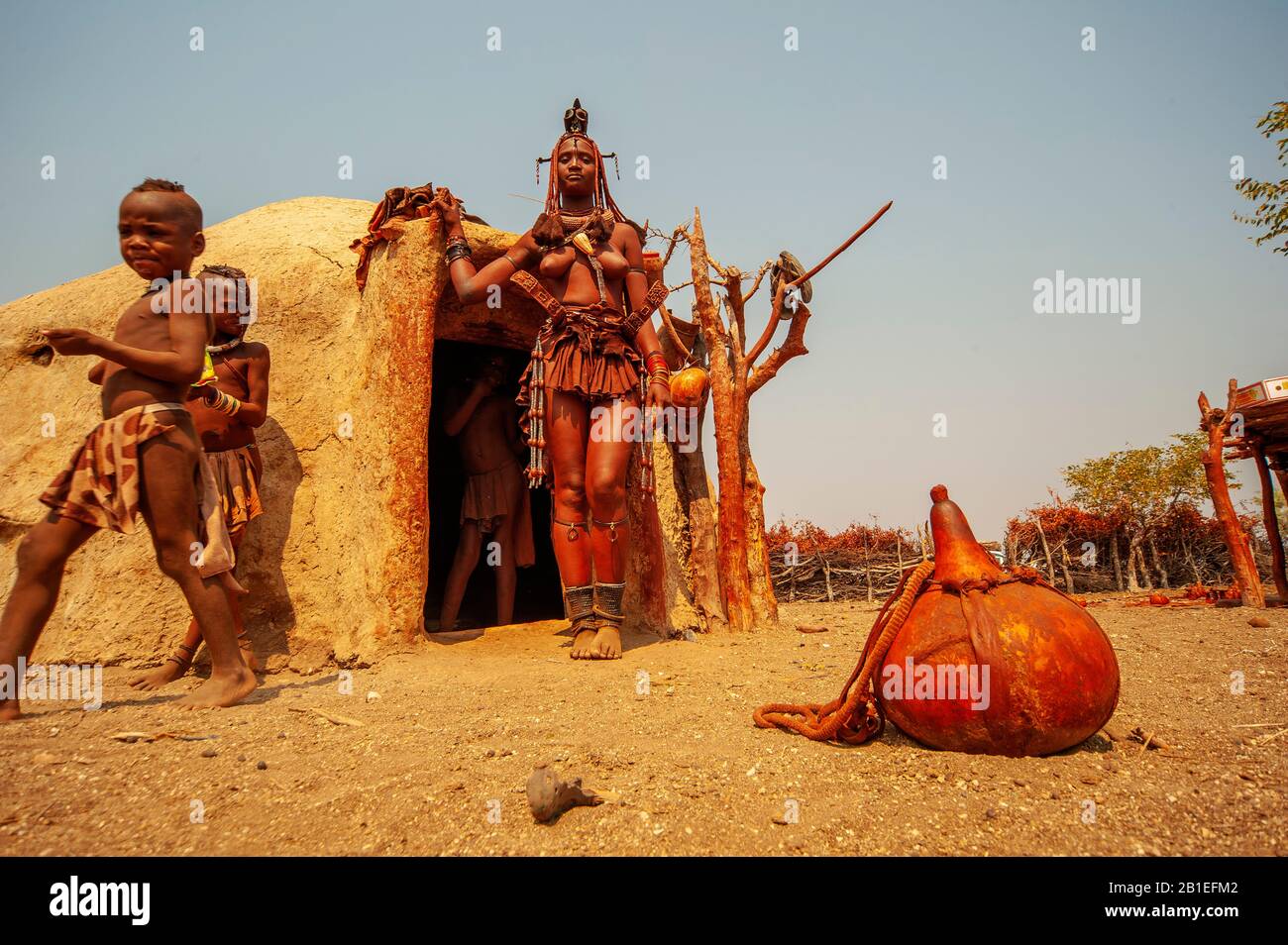 Himba woman wearing traditional clothes with his kids in front of their ...