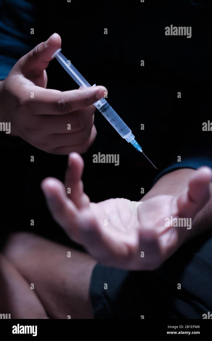 Man hand holding syringe, drug addiction concept Stock Photo - Alamy