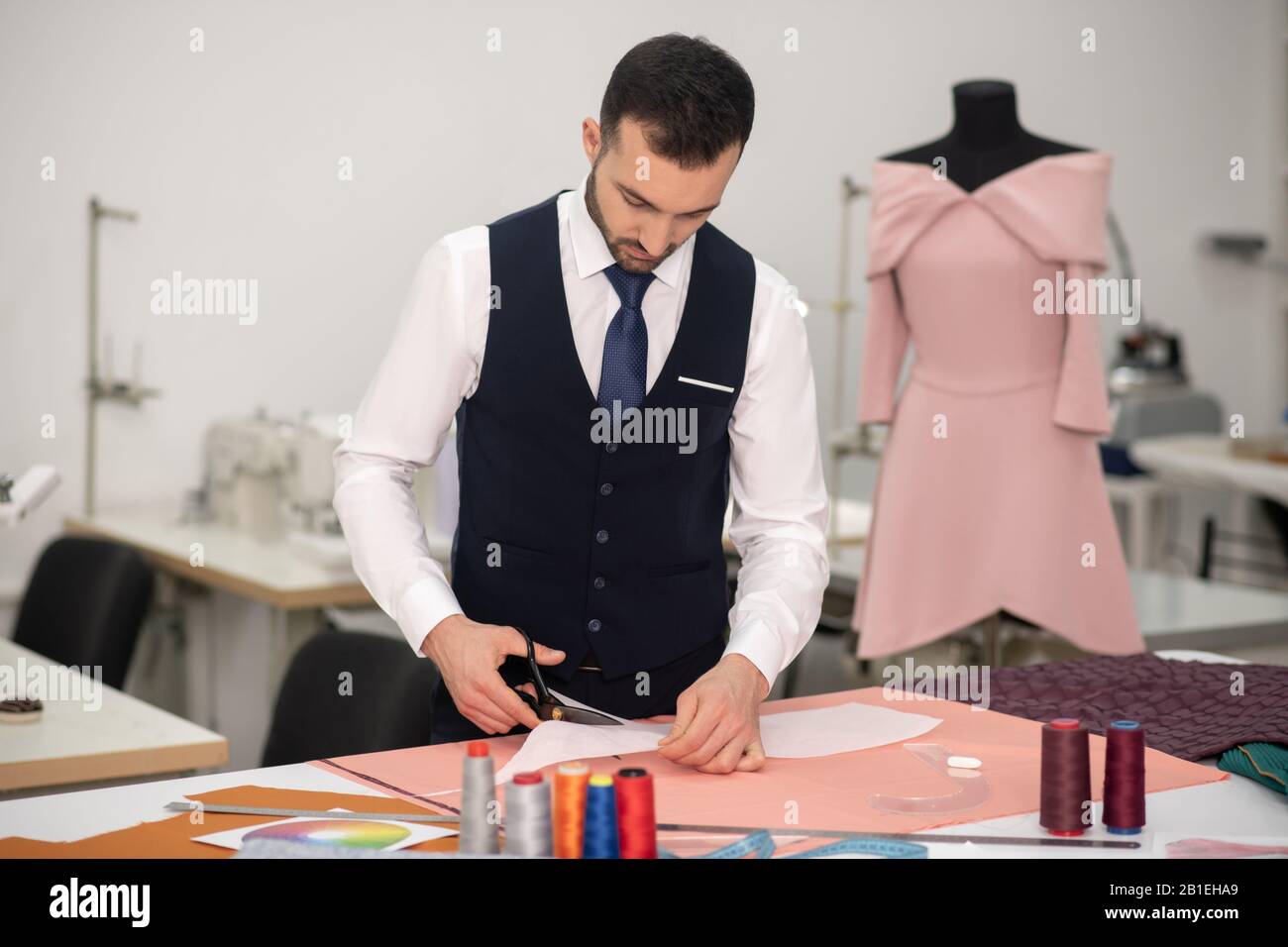 Male tailor standing and cutting out paper pattern Stock Photo - Alamy