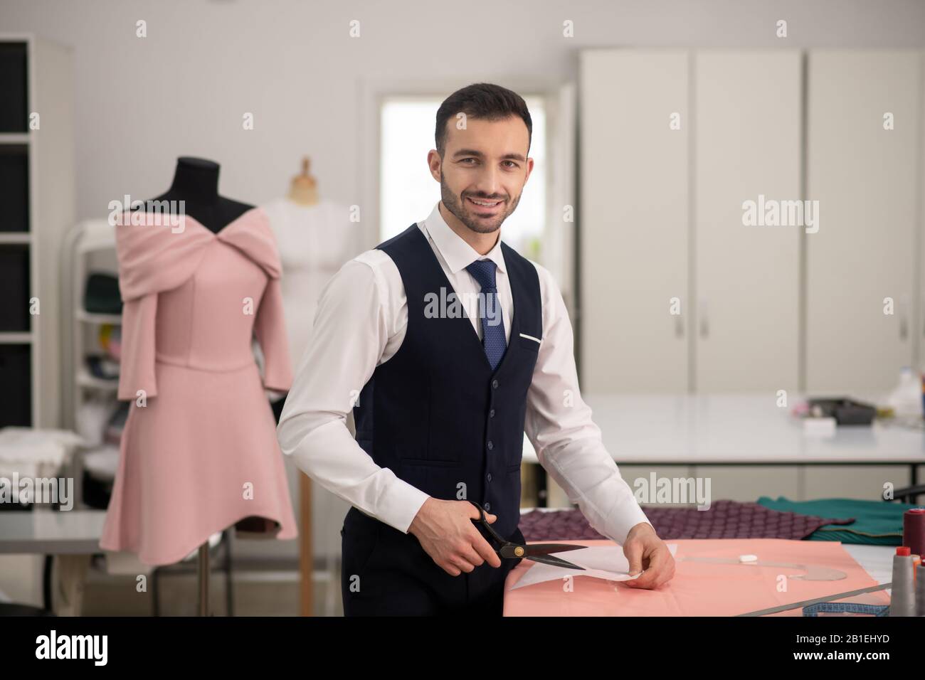 Male tailor cutting out paper pattern and smiling Stock Photo - Alamy