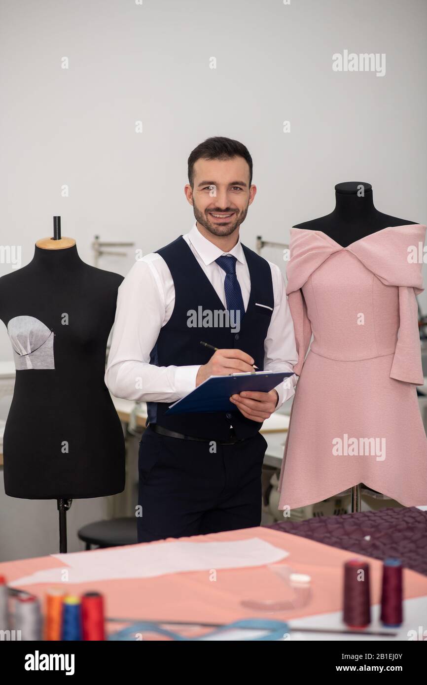 Male tailor standing next to dummy and making notes Stock Photo - Alamy
