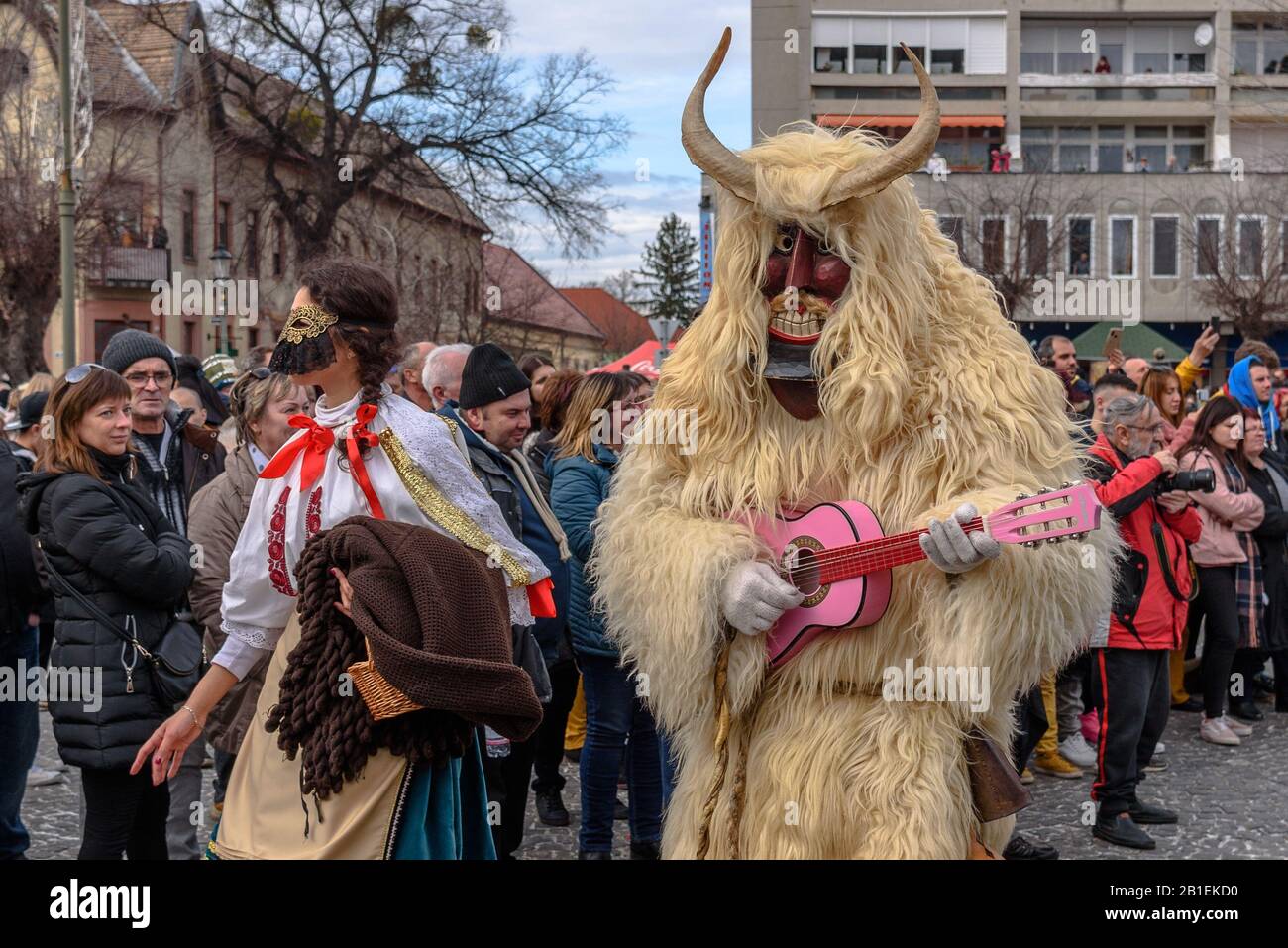 A masked buso and traditionally dressed woman walking in the procession ...