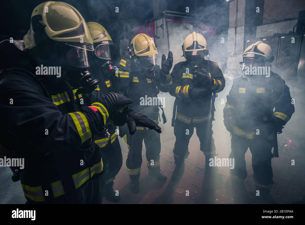 Firemen in uniform wearing gloves and gas masks inside the fire ...