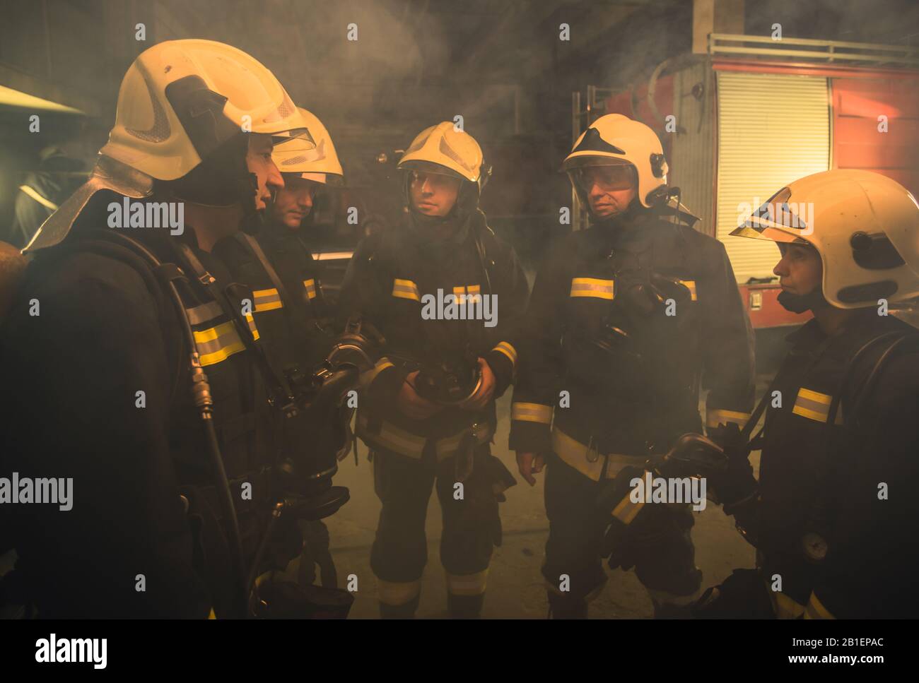 Group of firefighters with uniform inside the fire station preparing ...