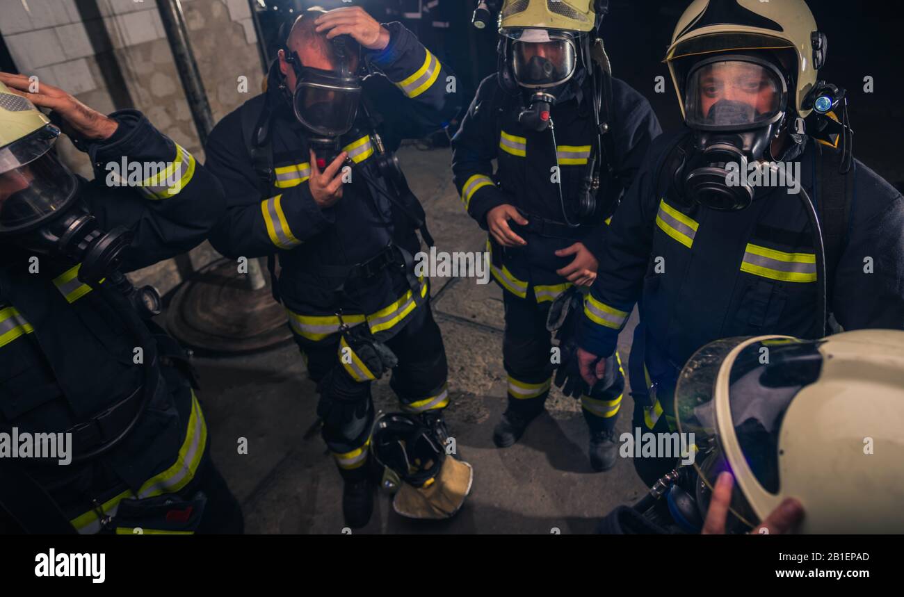 Group of firefighters standing inside the fire brigade wearing helmet ...