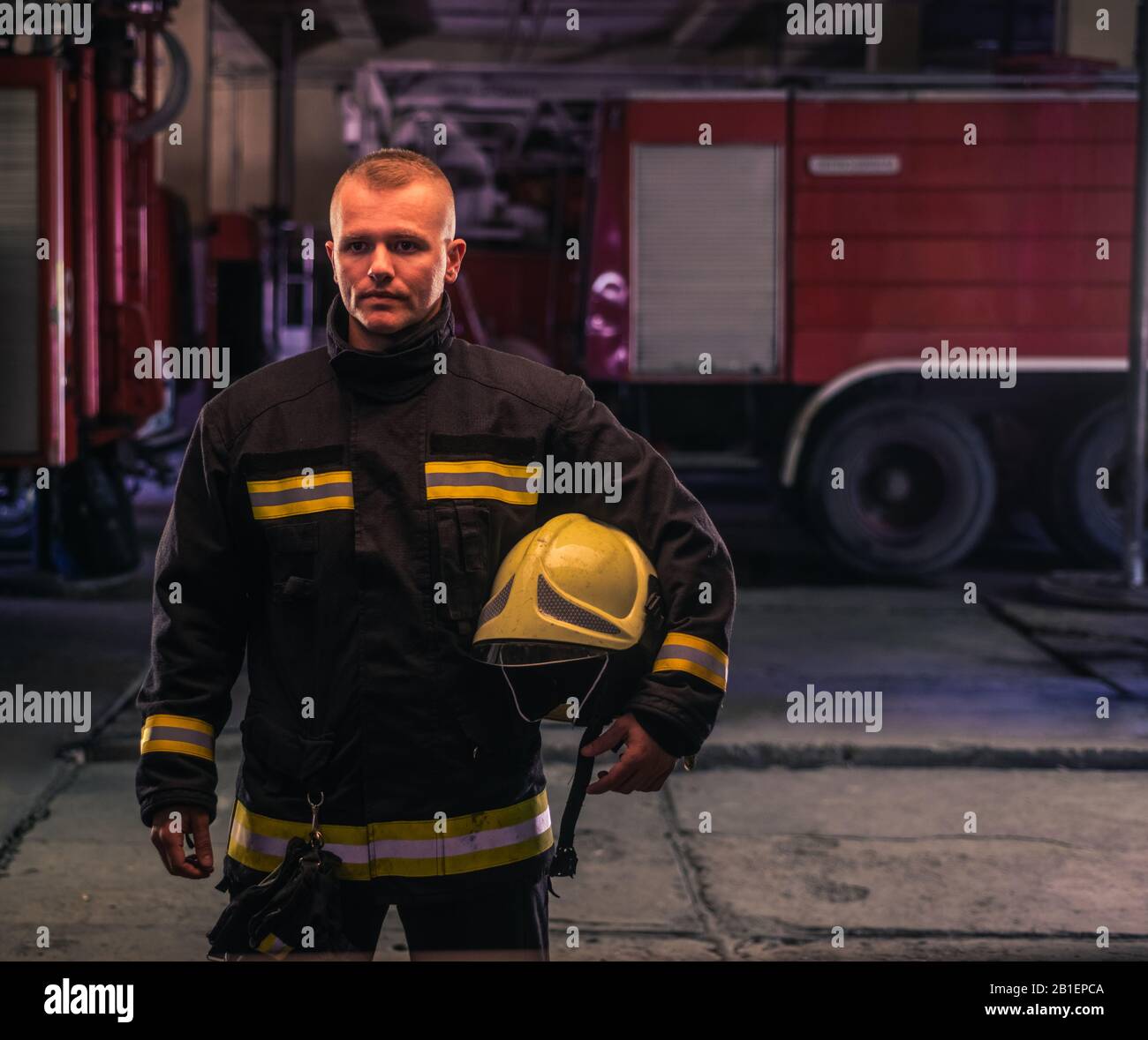 Portrait of young fireman standing inside the fire station Stock Photo ...
