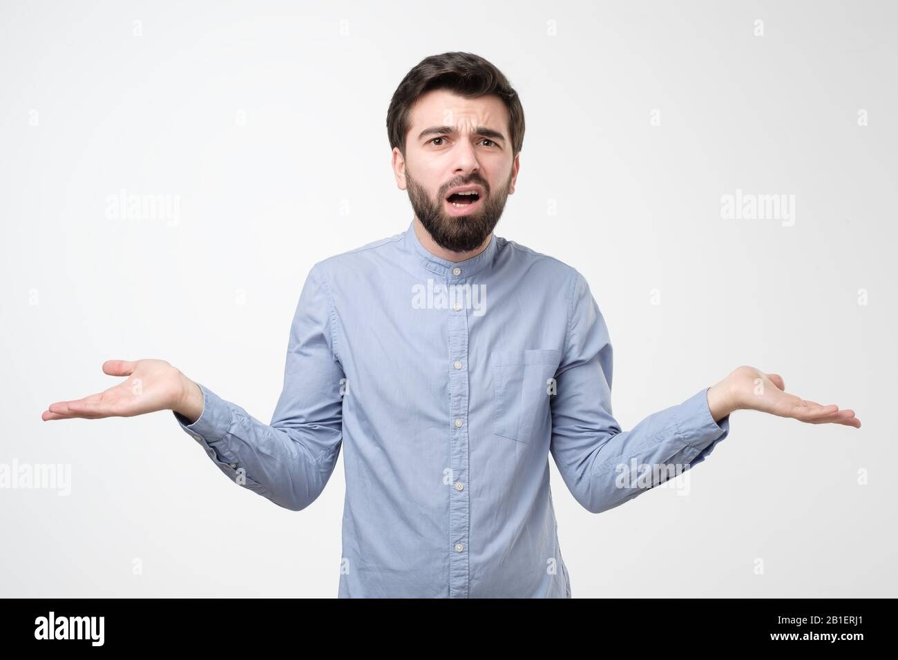 Guy feeling confused spreading palms and shrugging with awkward unaware ...
