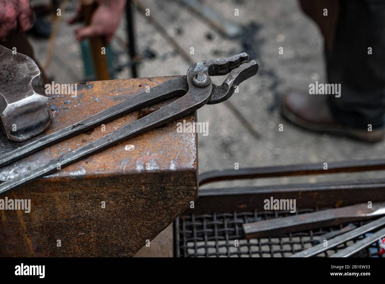 Metal tongs over the anvil - blacksmith equipment Stock Photo - Alamy