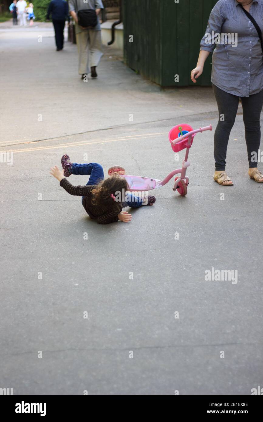 Street accident - kid girl fell down from pink child scooter Stock ...