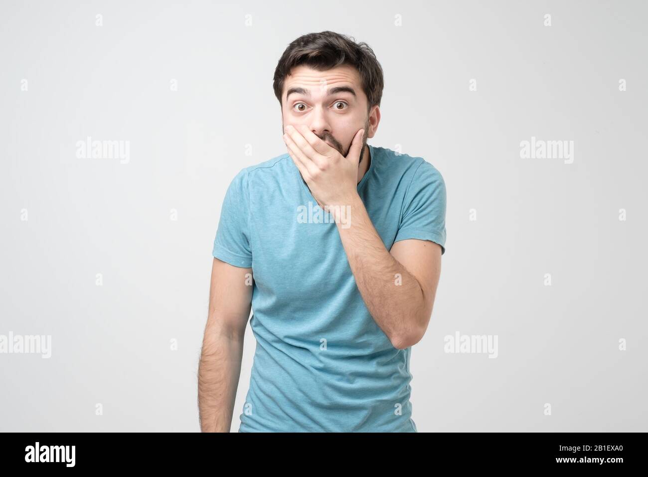 Handsome hispanic man covering mouth with hand. He lost his voice from ...