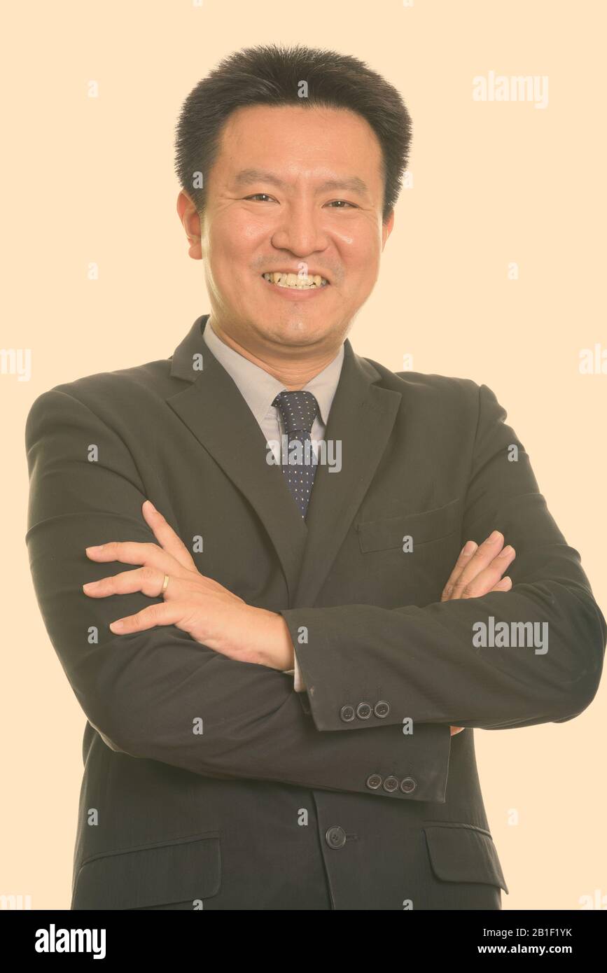 Studio shot of happy Japanese businessman smiling with arms crossed ...