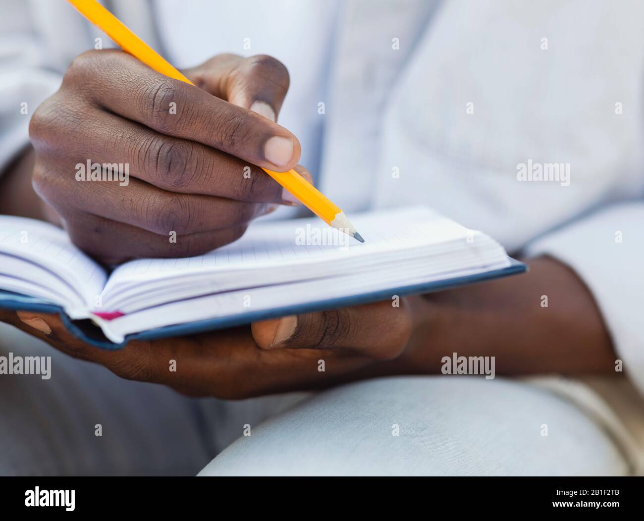 Close up of afro student taking notes, using notepad and pencil Stock ...