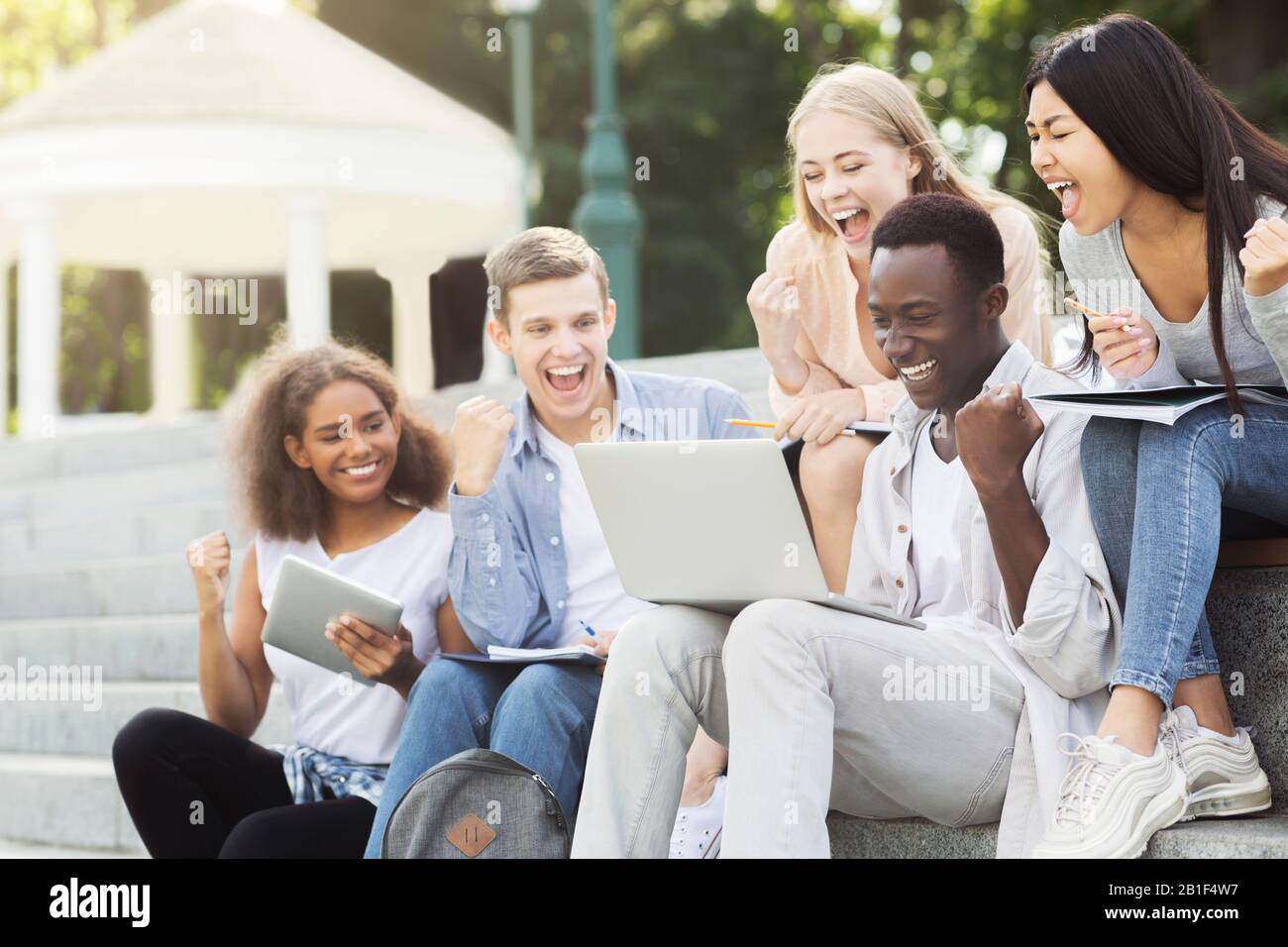 Group of multiracial students celebrating success, checking exam ...