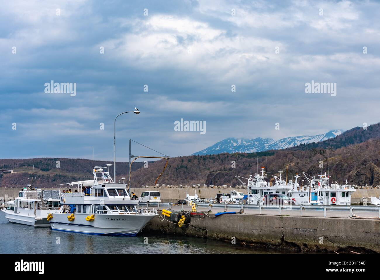 View of Utoro fishing port in springtime with Shiretoko mountain range ...