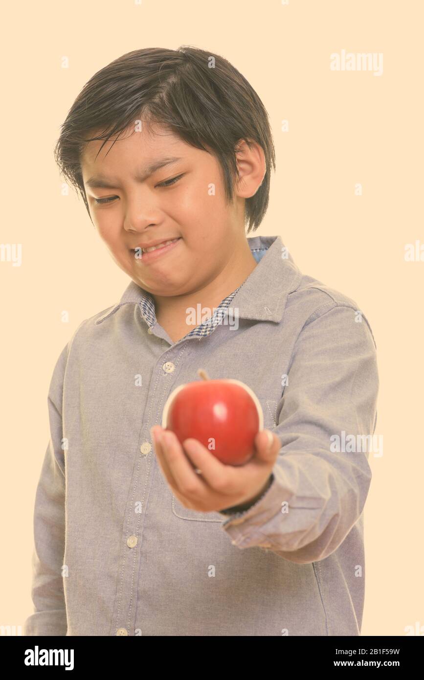 Studio shot of cute Japanese boy holding red apple and looking ...