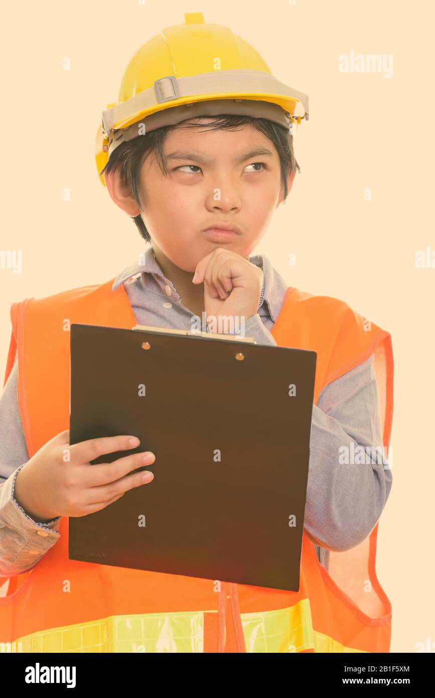 Studio shot of cute Japanese boy construction worker holding clipboard ...