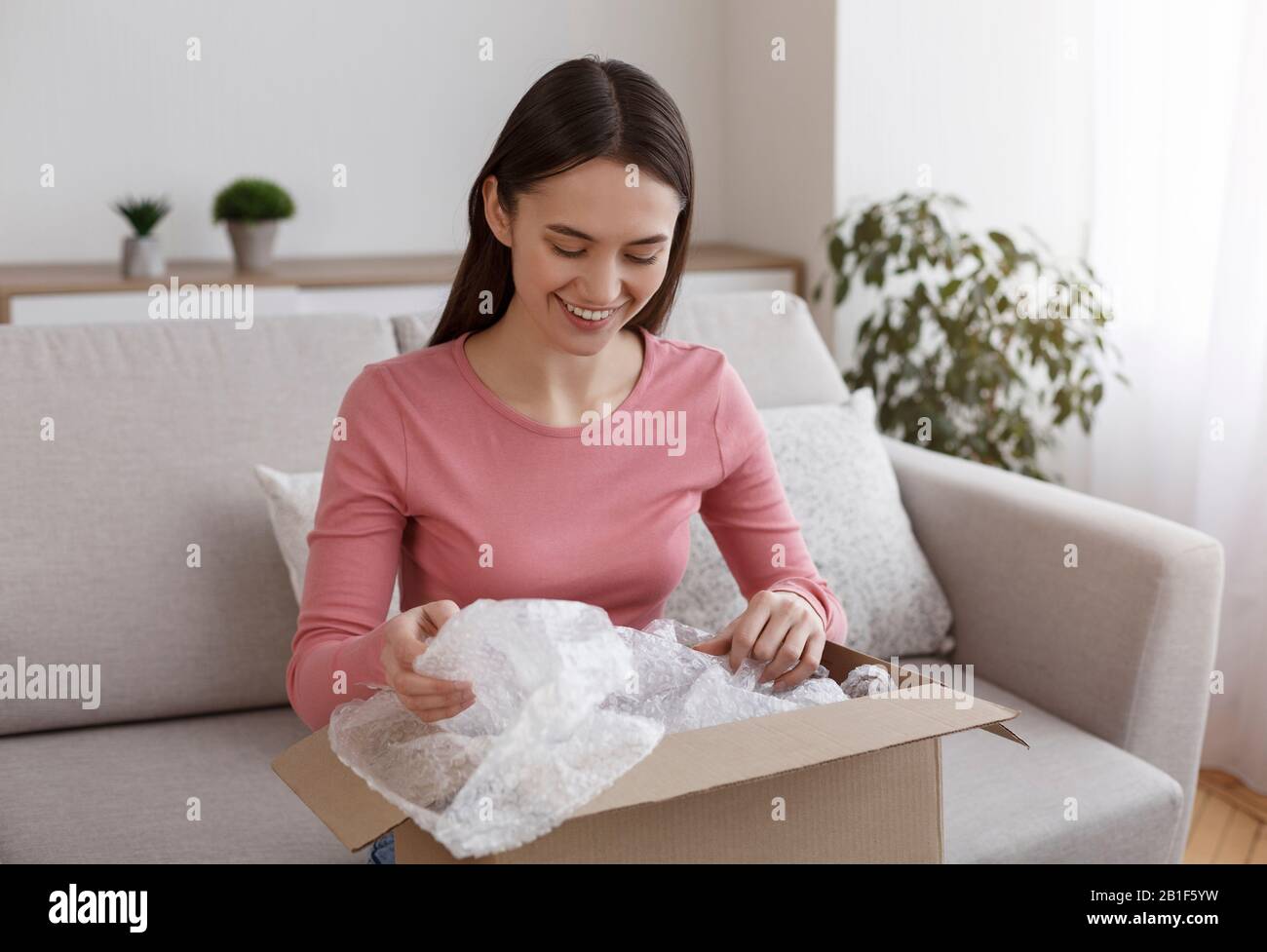 Attractive young girl unboxing international delivery order Stock Photo ...