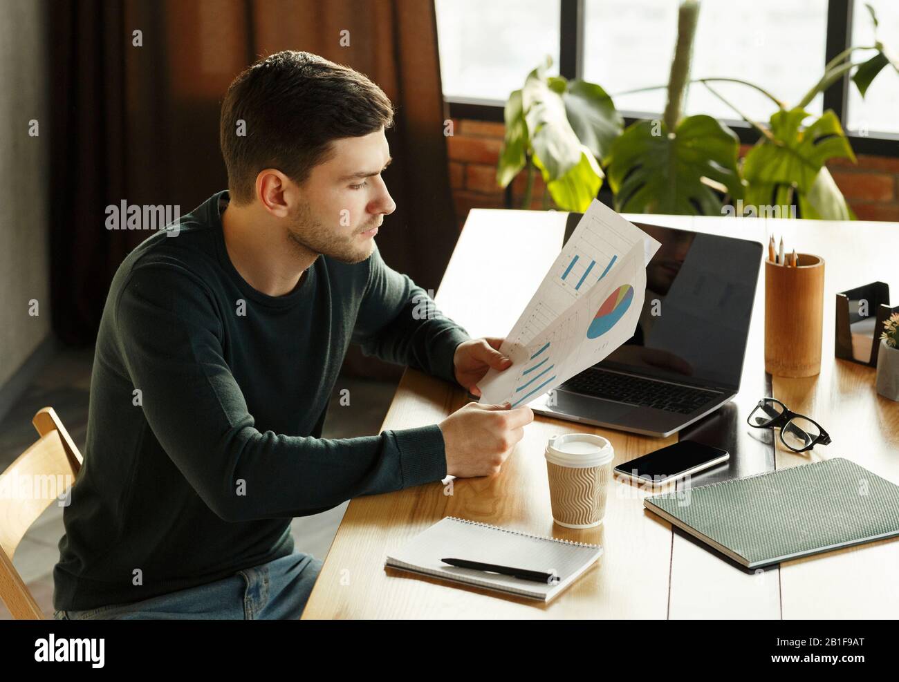 Manager Looking At Graphs And Charts Sitting In Modern Office Stock ...