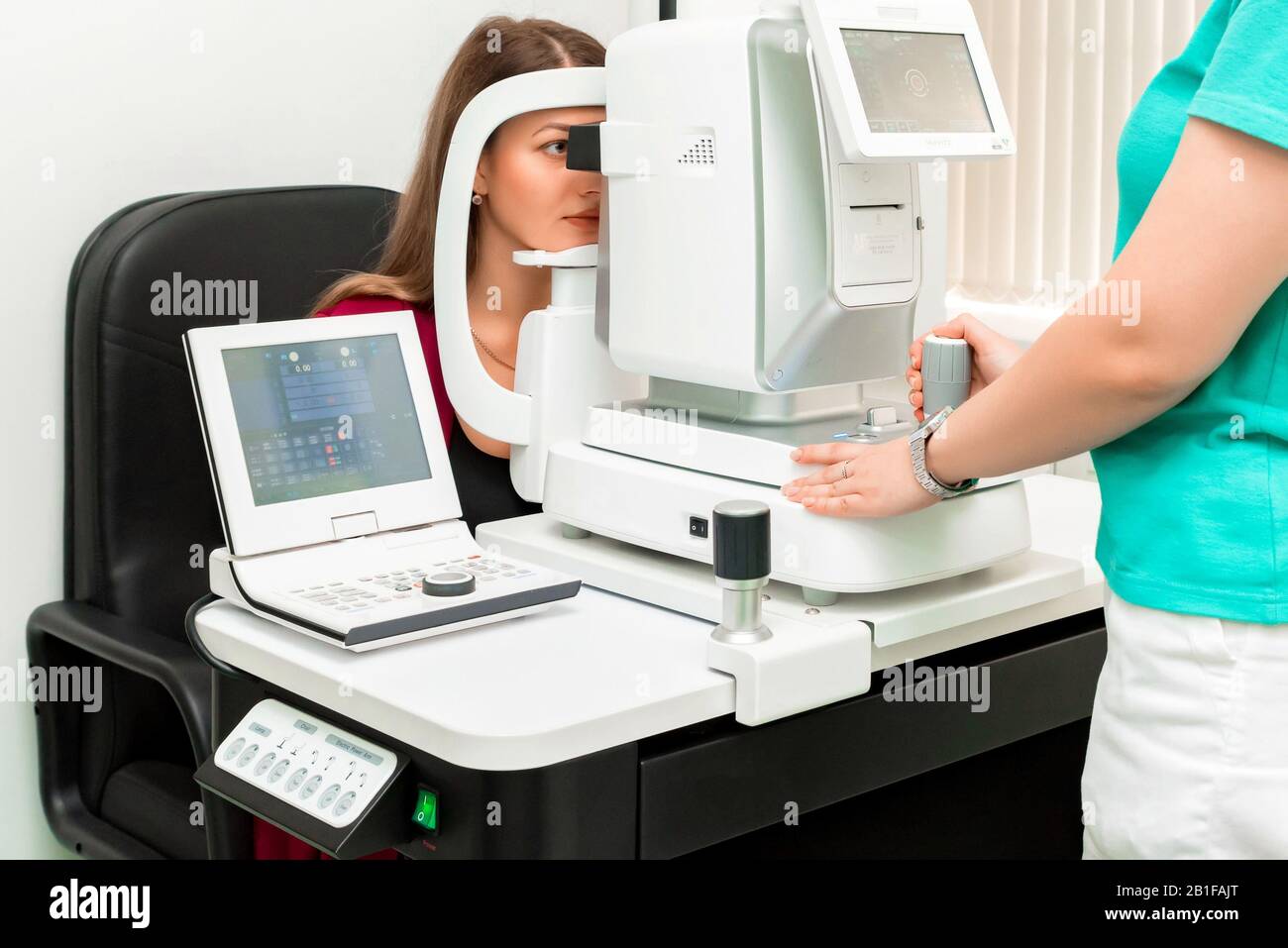 Beautiful woman having an eye lens exam with auto refractor keratometer ...