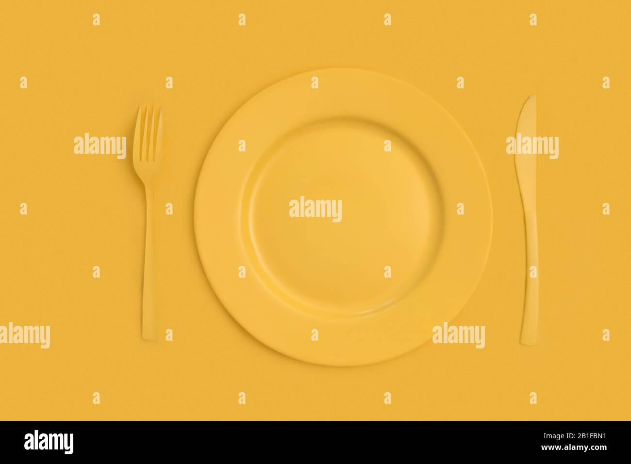 Yellow dishes: plate, knife and fork. on a yellow background, top view ...