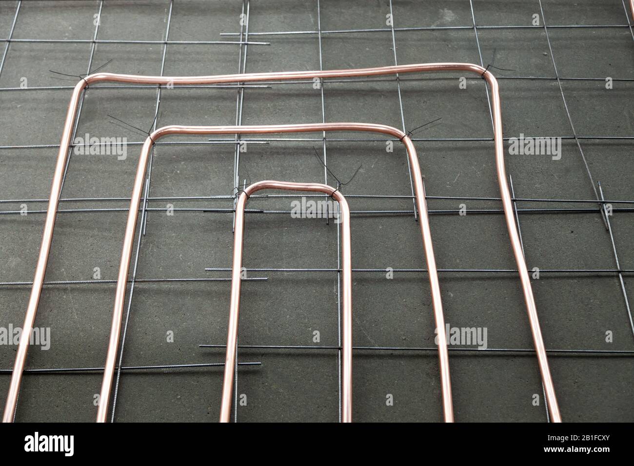 Close up bent new copper pipe on floor, lay pipeline, installation ...