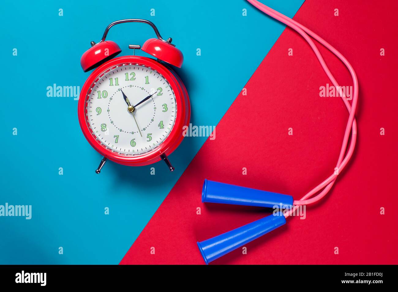 Red alarm clock and jump rope on the color background. Fitness and ...