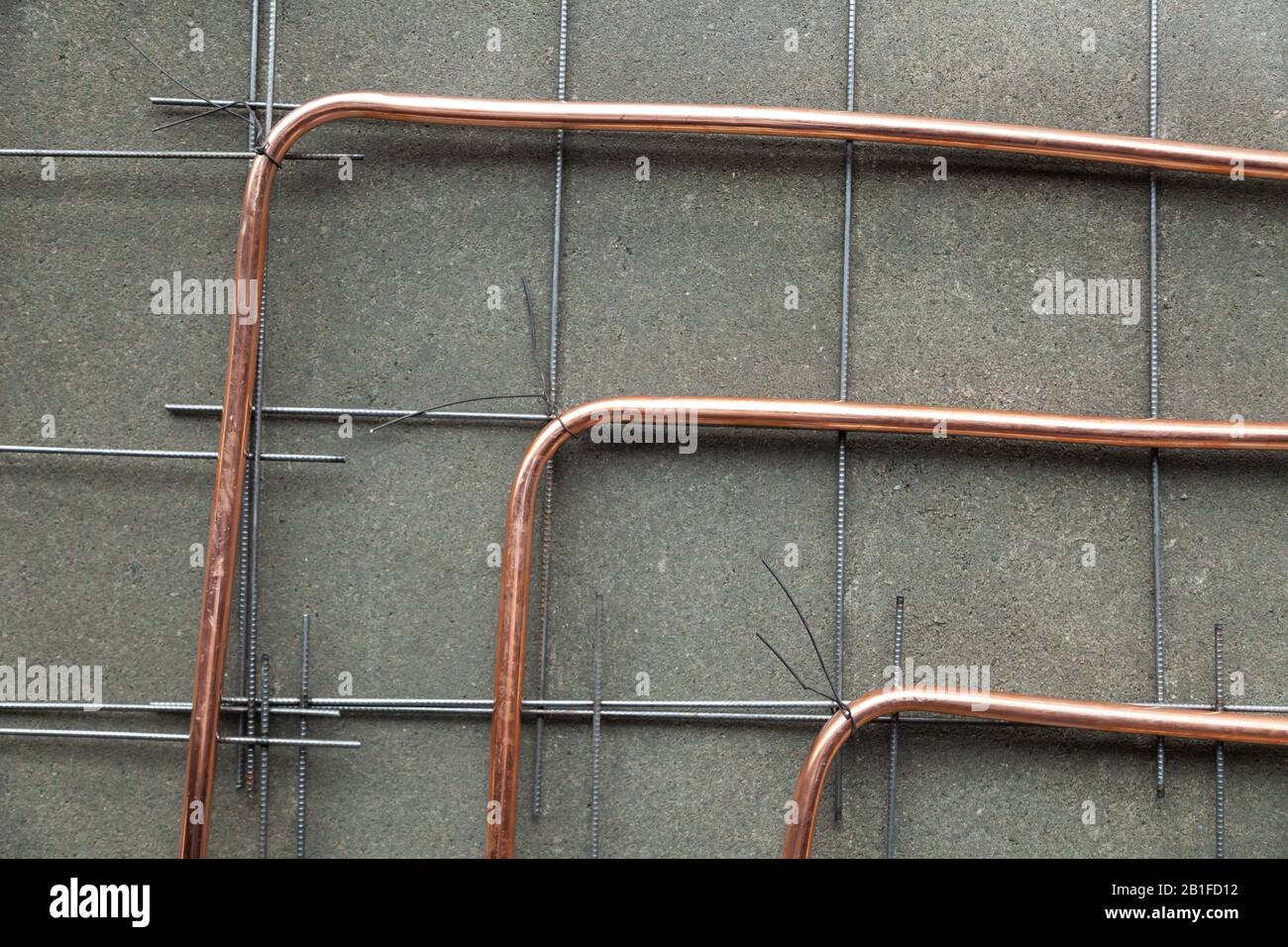 Close-up bent new shiny copper pipe on floor, lay pipeline ...