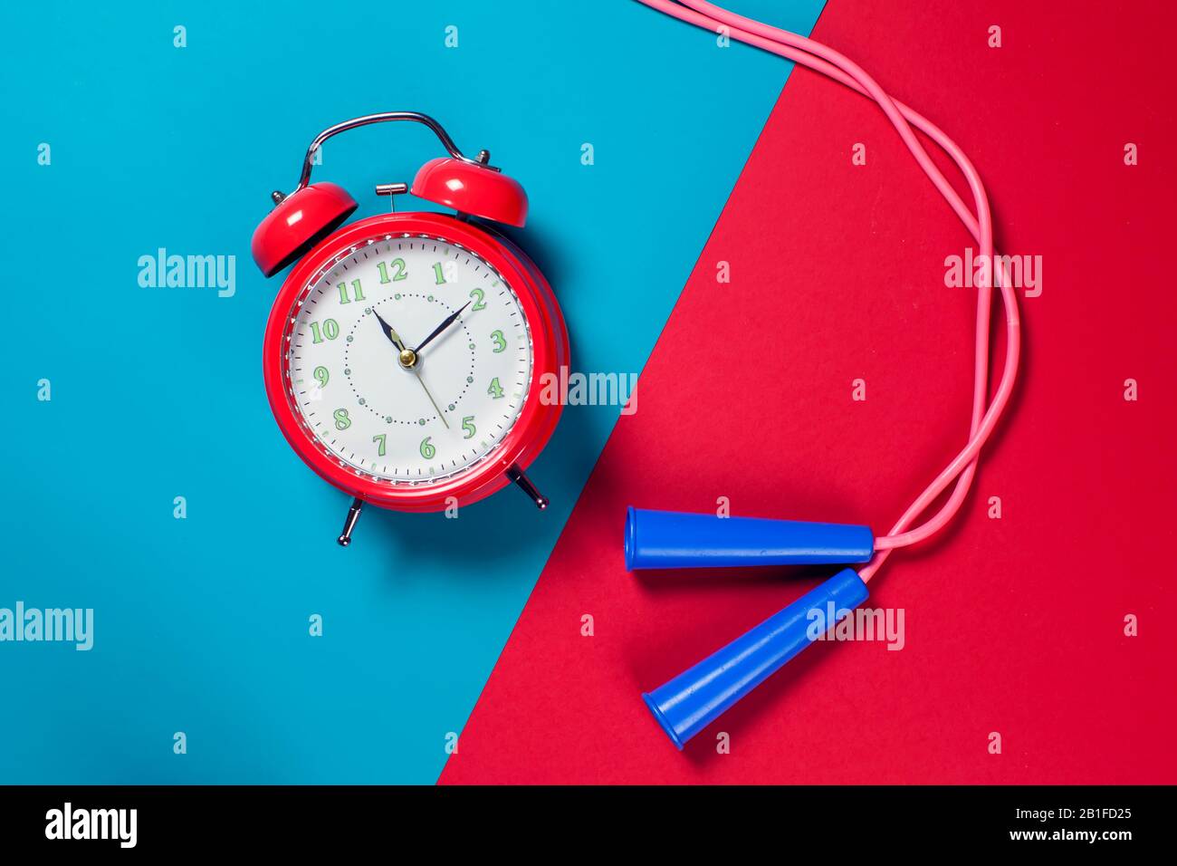 Red alarm clock and jump rope on the color background. Fitness and ...