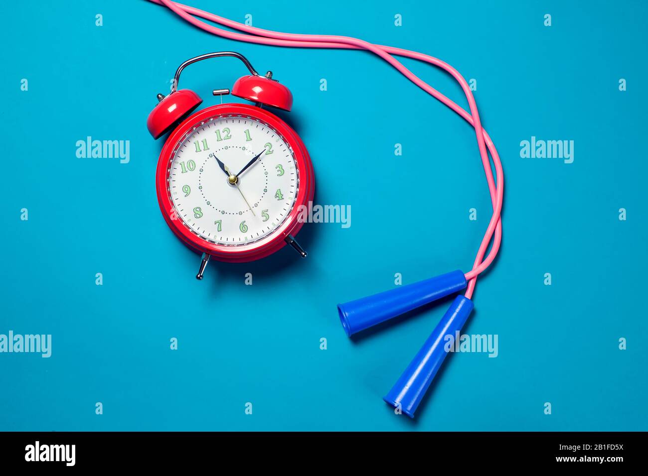 Red alarm clock and jump rope on the color background. Fitness and ...