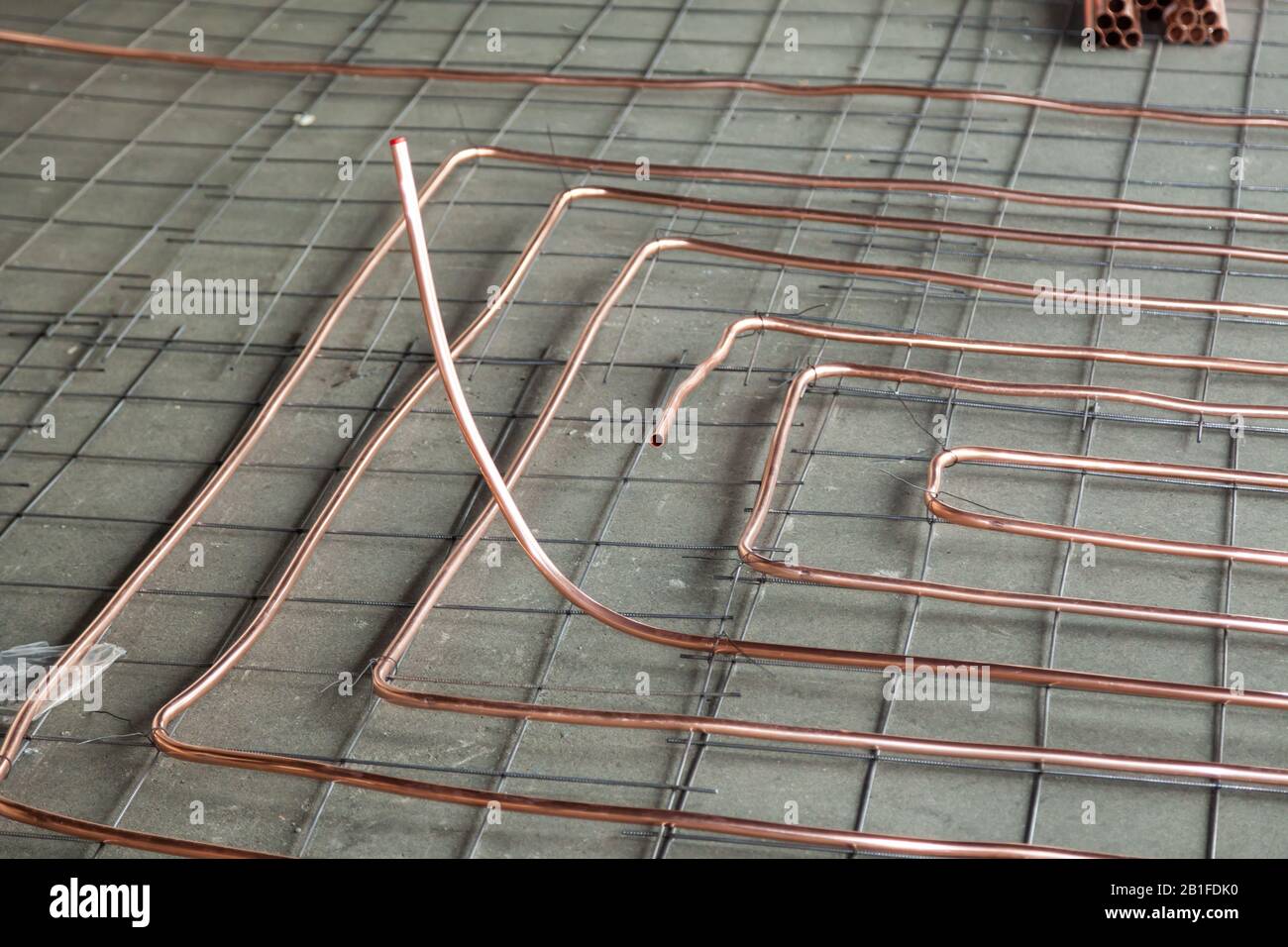 Close-up bent new shiny copper pipes on floor, laying pipeline ...