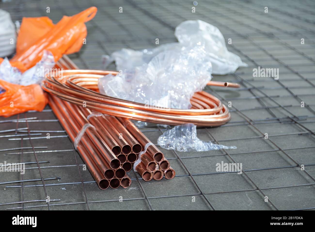 Close-up skein of new shiny copper pipes on floor, plastic package, lay ...
