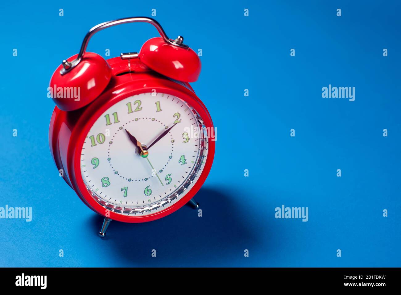 Red alarm clock on the color background Stock Photo - Alamy