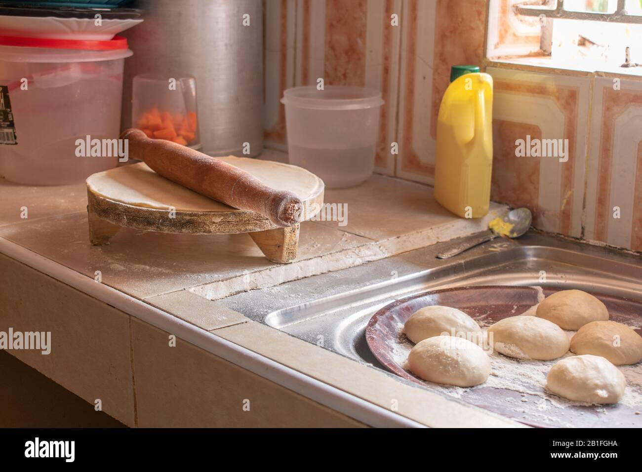 rolling pin on a counter of a small crowded kitchen next to chapati ...
