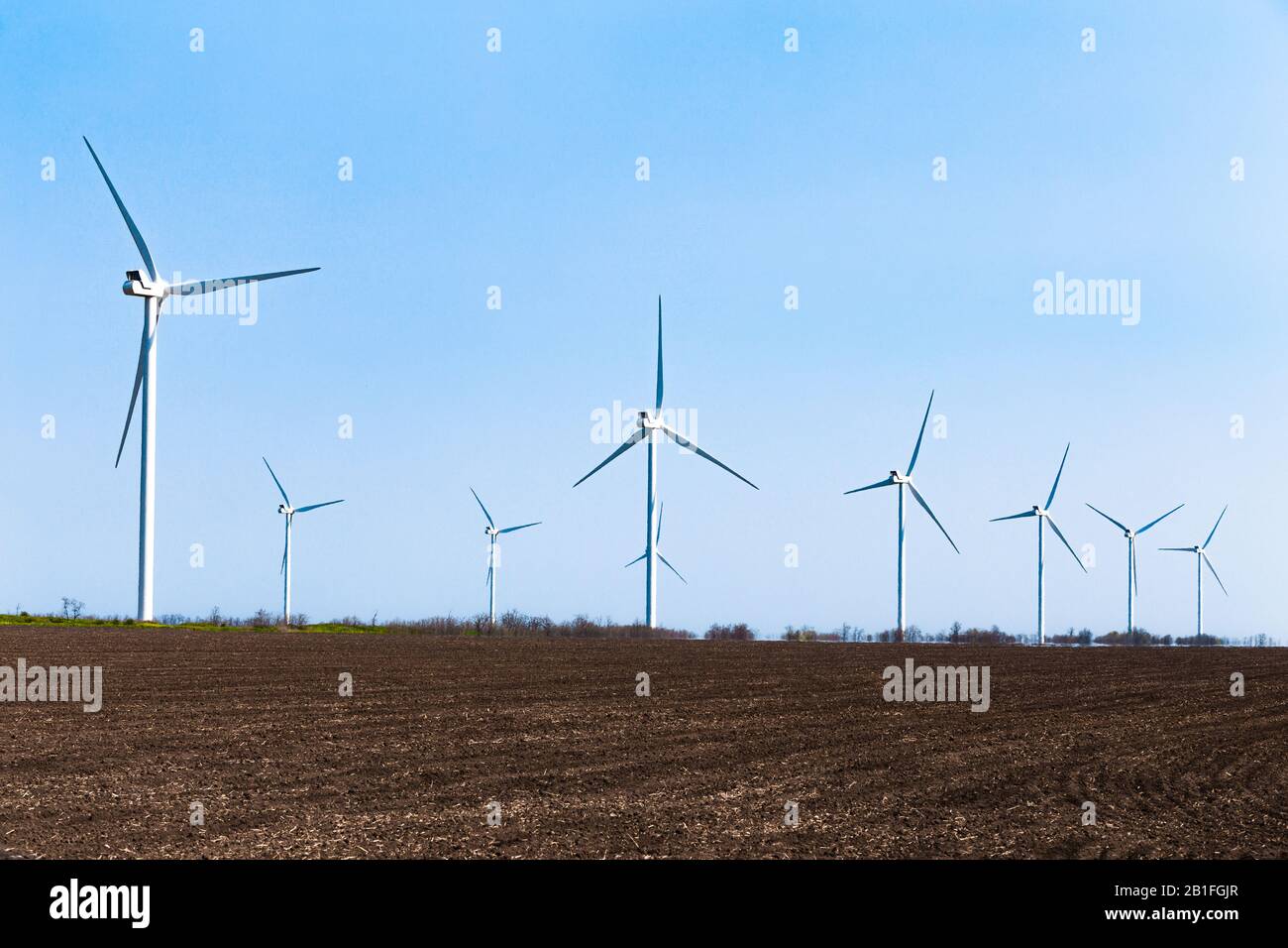 Wind turbines on blue sky background, Brown field Stock Photo - Alamy