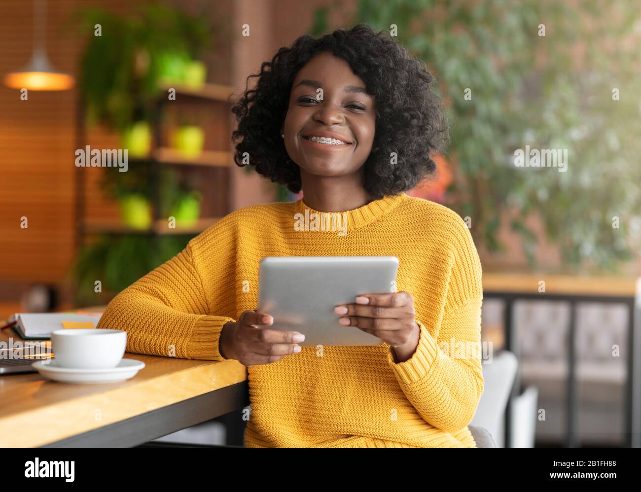 Happy african girl student using digital tablet at cafe Stock Photo - Alamy