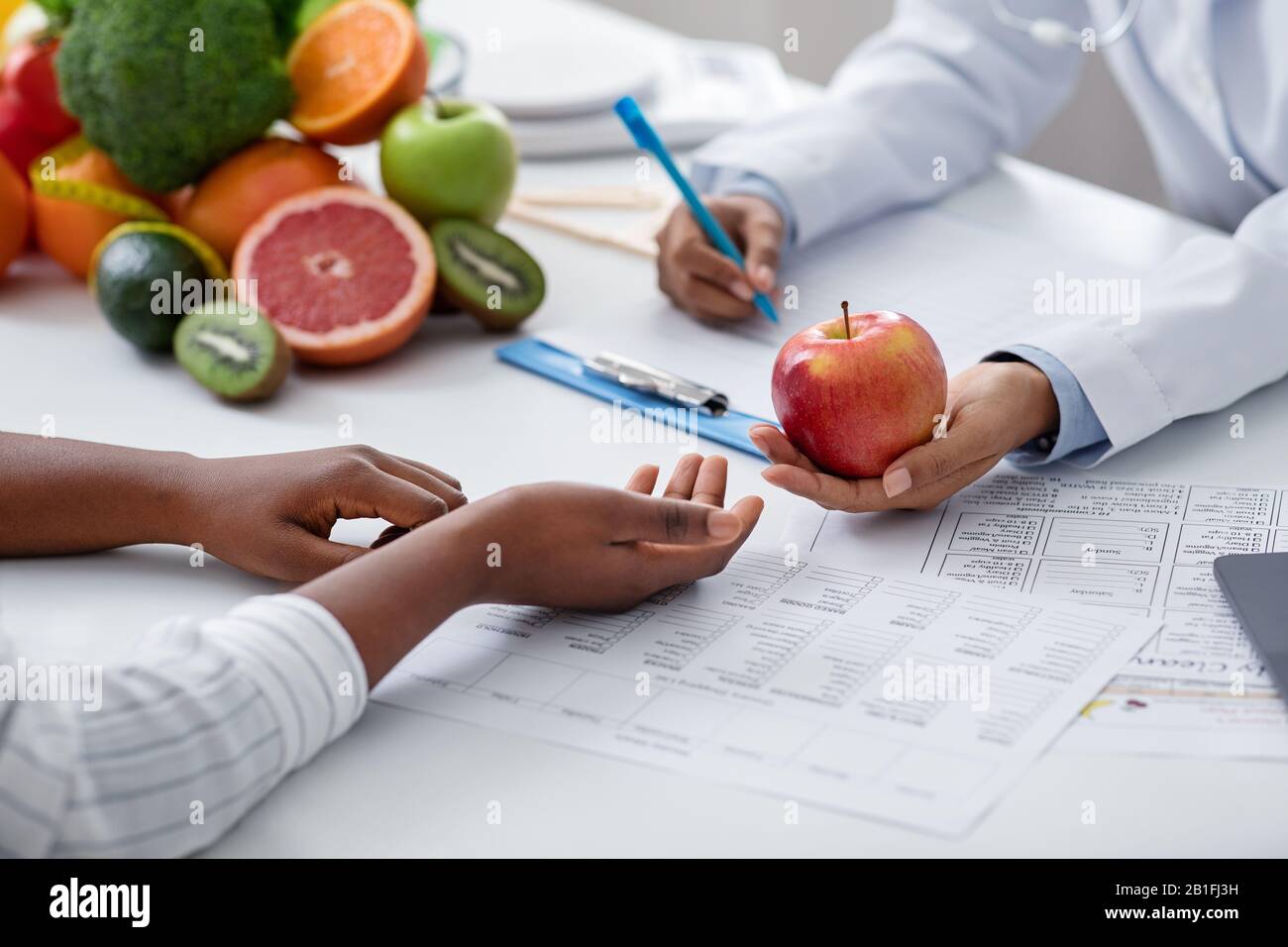Doctor giving apple to afro woman patient during session Stock Photo ...